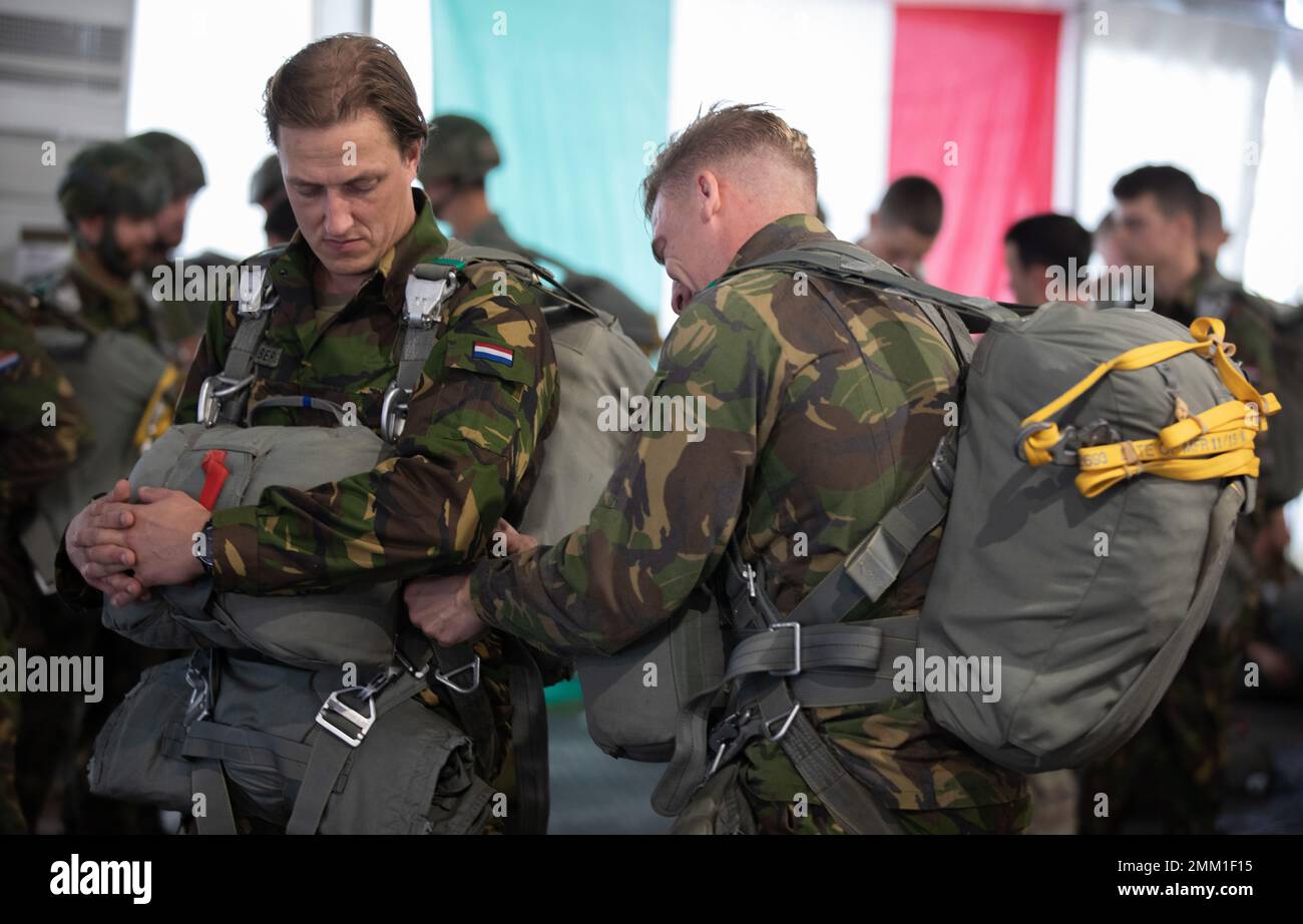 Two Dutch Paratroopers help one another rig up into a T-11 parachute ...