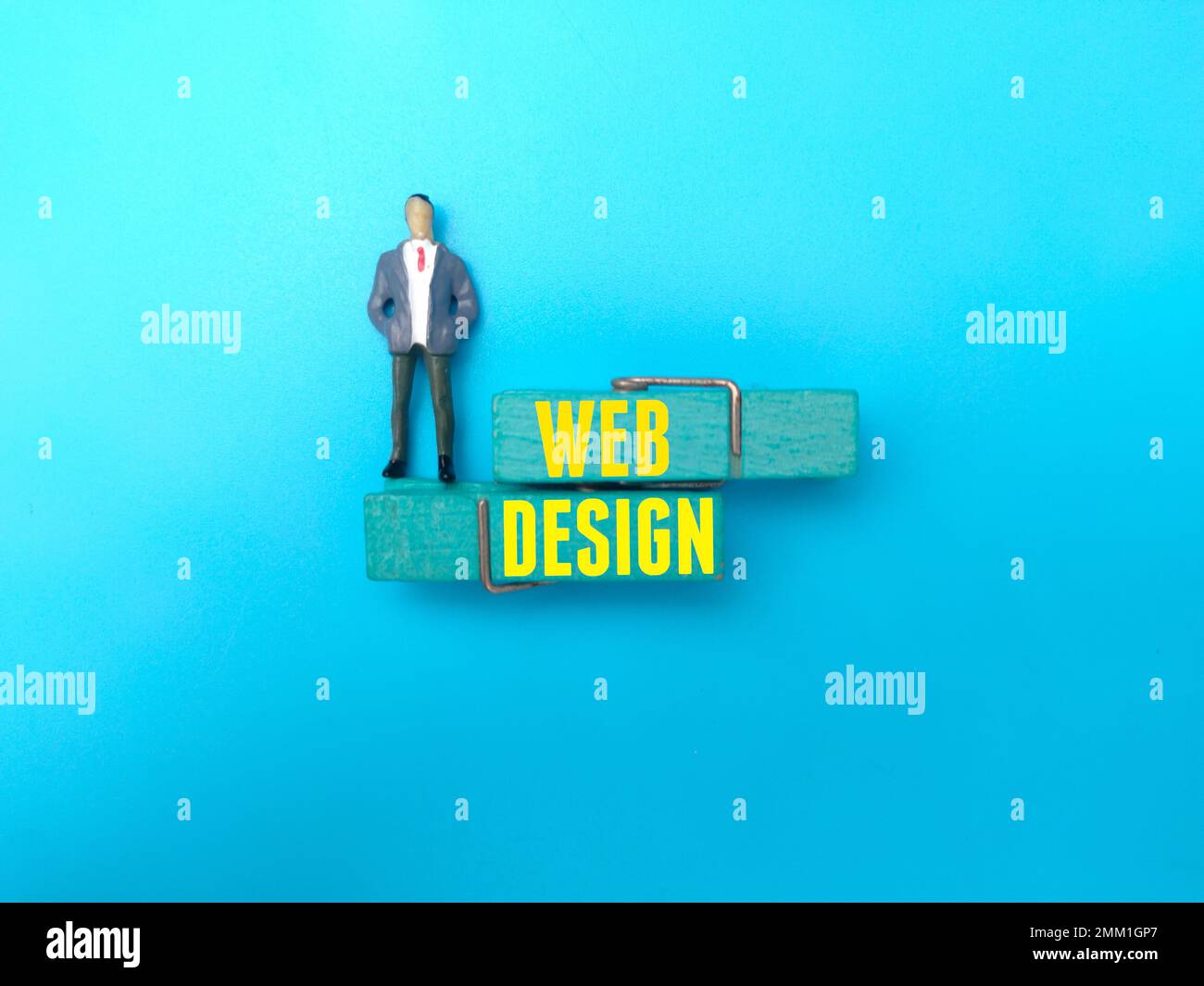 Miniature people and wooden clips with the word WEB DESIGN on blue ...