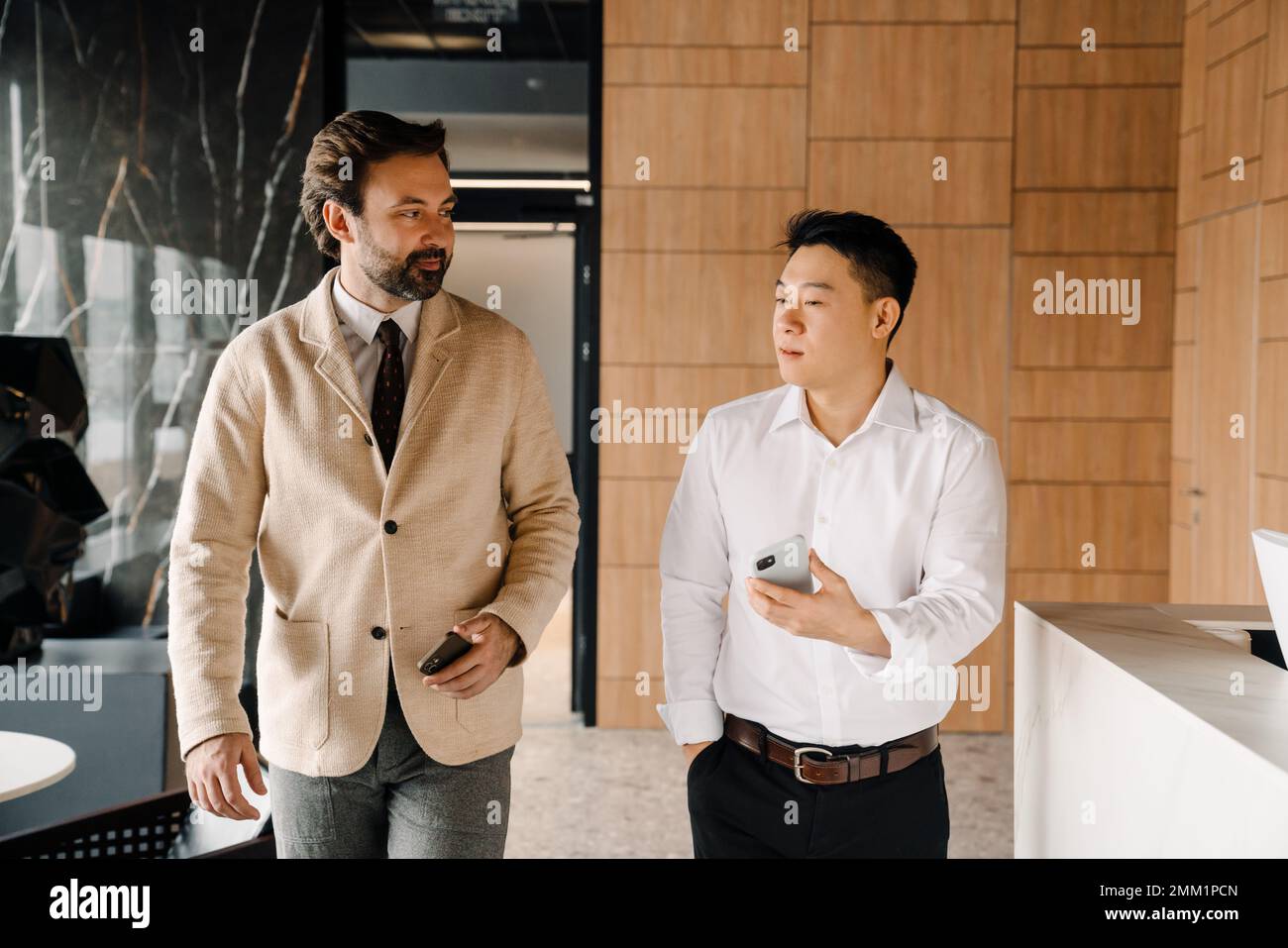 Two succesful elegant business people talk and walk holding their ...