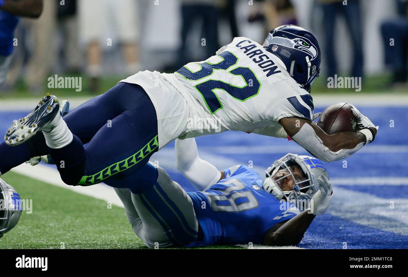 Seattle Seahawks running back Chris Carson (32) goes over Detroit Lions ...