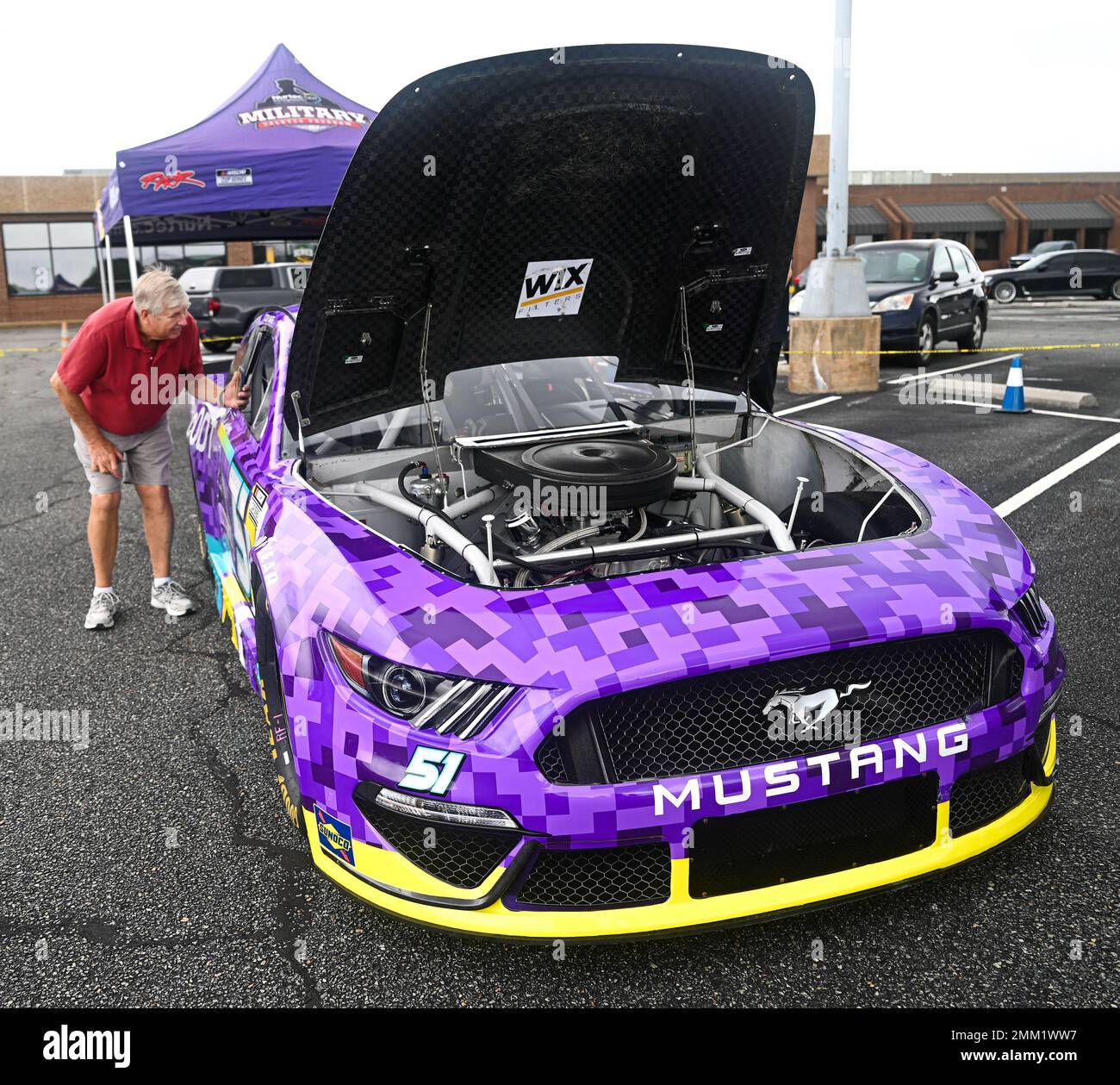 A NASCAR fan admires a Rick Ware Racing Team race car parked outside ...