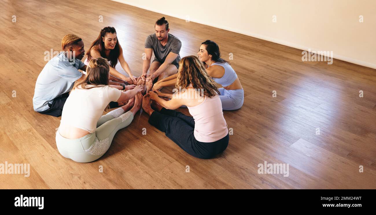 Happy people doing the head to knee yoga pose while sitting together in ...