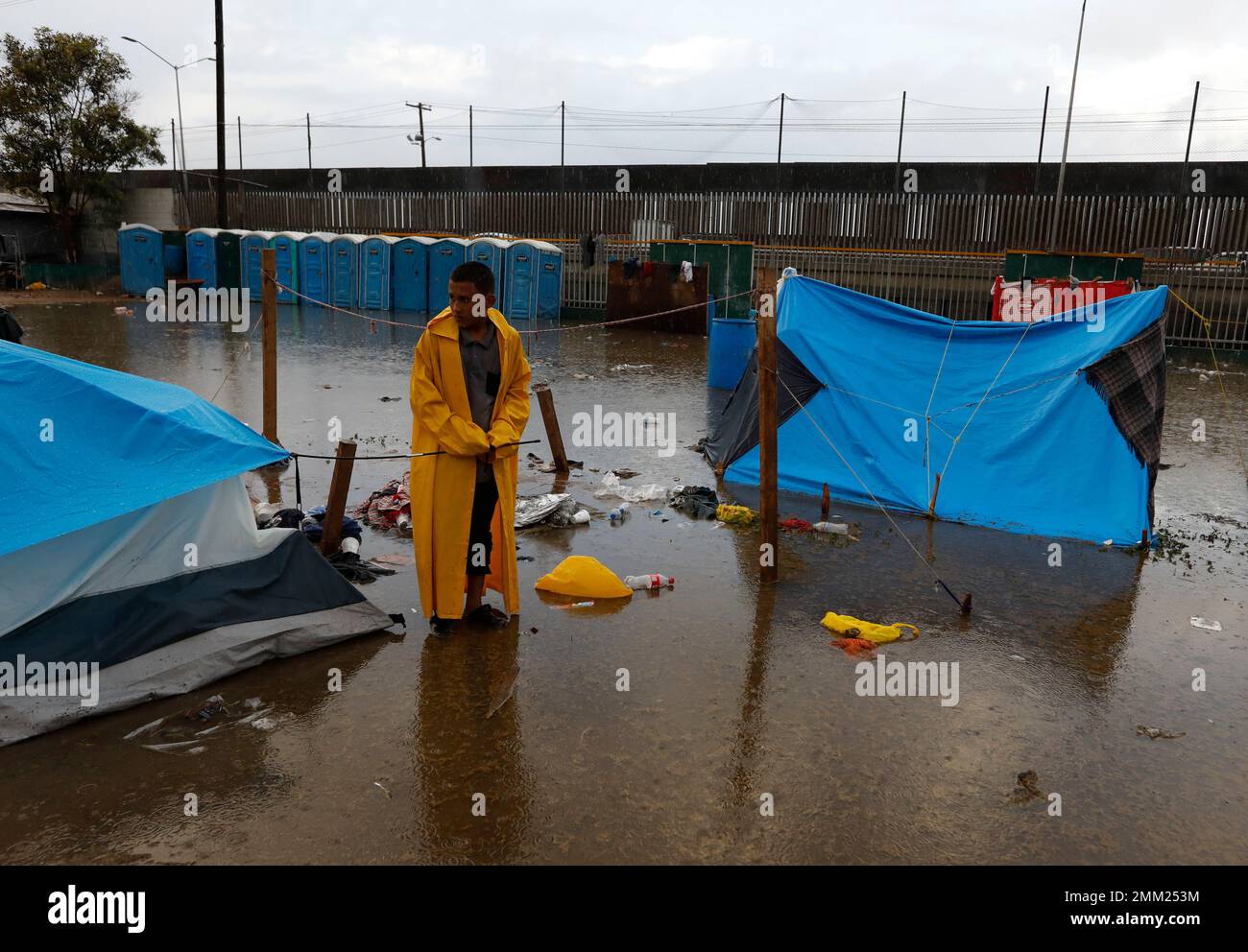 A boy examines a flooded tent between bouts of heavy rain at a sports ...
