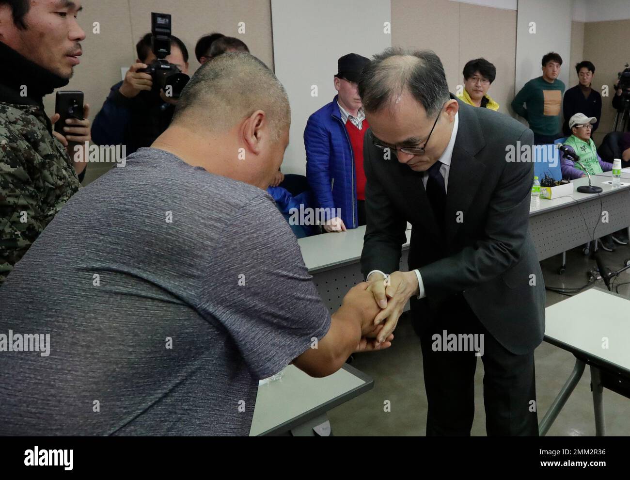 South Korea's Prosecutor General Moon Moo-il holds hands with a former inmate upon his arrival ...