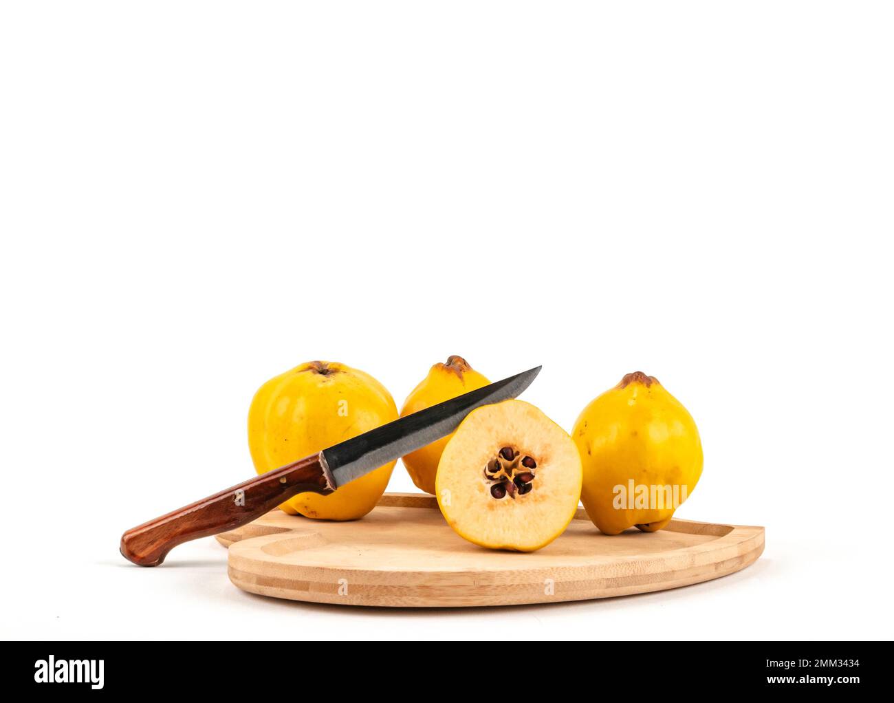 Quince cutted with knife from half seeds appear on wooden cutting board ...