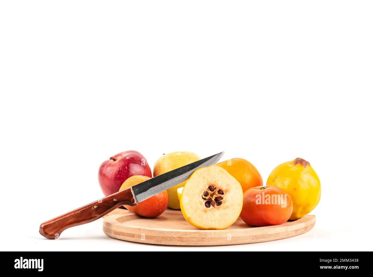 Half cutted quince and fruits on a wooden plate with knife white ...
