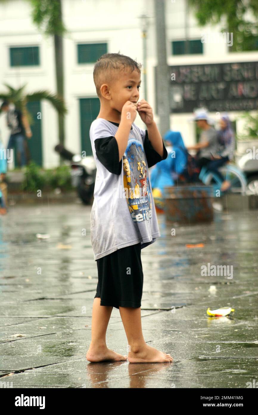 portrait of a boy standing in the pouring rain putting food in his ...