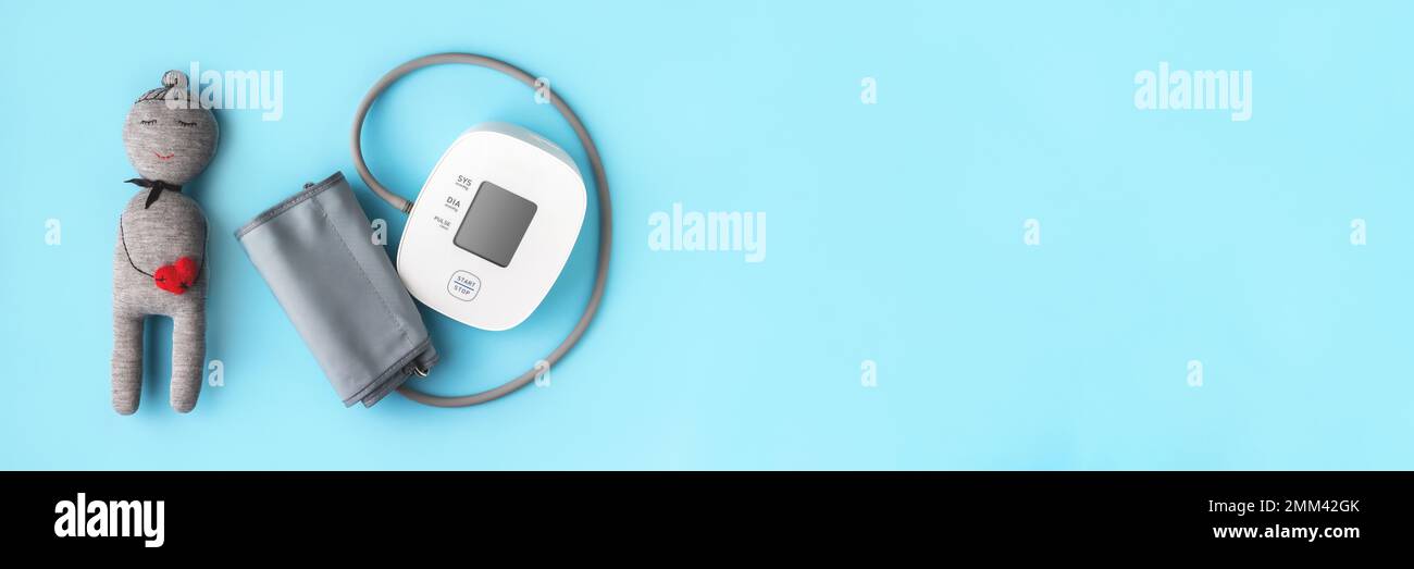Automatic blood pressure monitor and cute soft toy with heart on blue ...