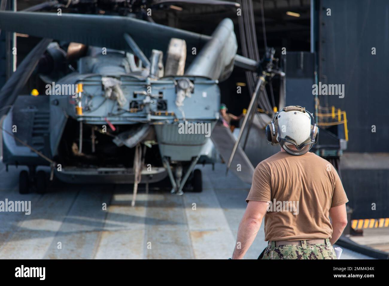 A U.S. Navy Sailor with Helicopter Mine Countermeasures Squadron 14 guides an MH-53 helicopter ...