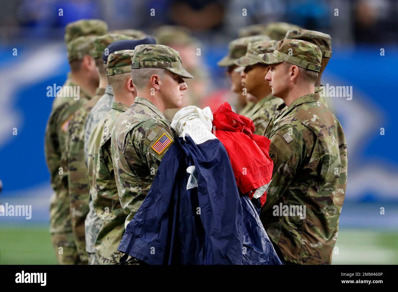 Military personnel hold an American flag before an NFL football game ...