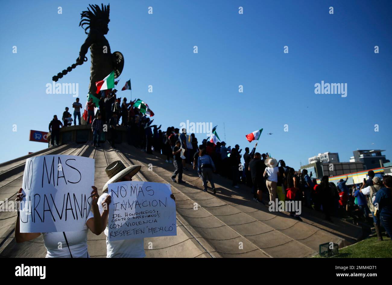 Demonstrators stand under an statue of Aztec indigenous ruler ...