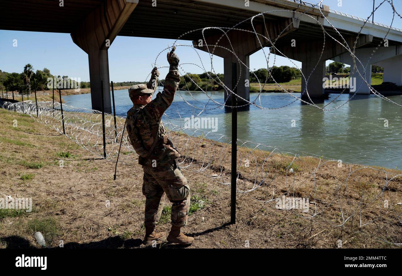 A member of the U.S. military helps install concertina wire along the ...