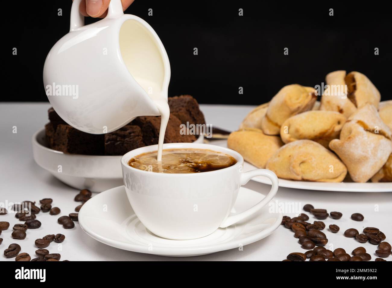 Cream from the milk jug is poured into coffee, making coffee with cream ...