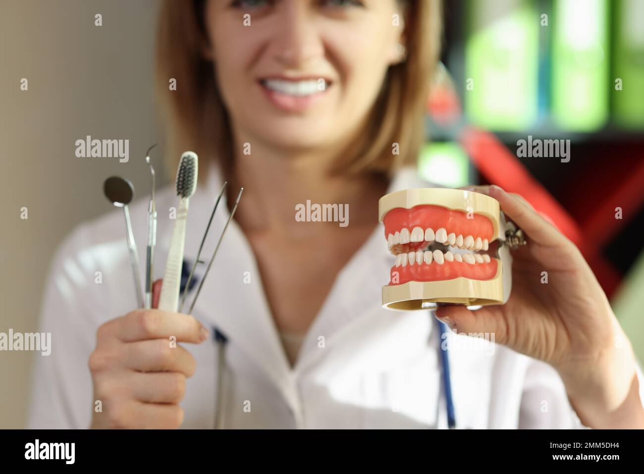 Woman dentist shows medical tools with toothbrush and teeth model Stock ...