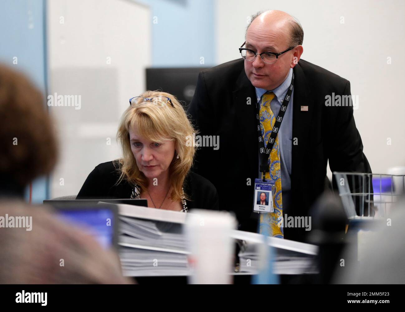 Maine Secretary of State Matthew Dunlap looks over the shoulder of ...