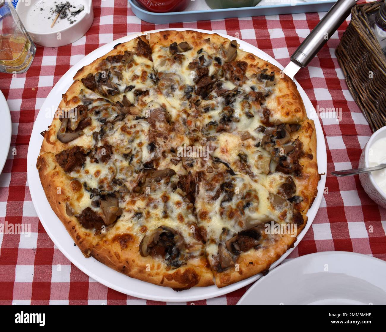Delicious pizza with lamb serving on a table with plaid tablecloth in a ...