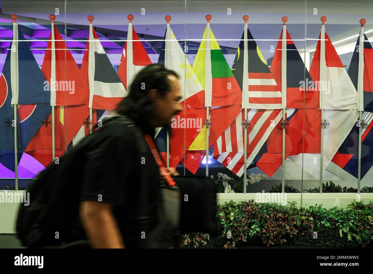 A journalist walks past ASEAN member country flags at the Suntec ...