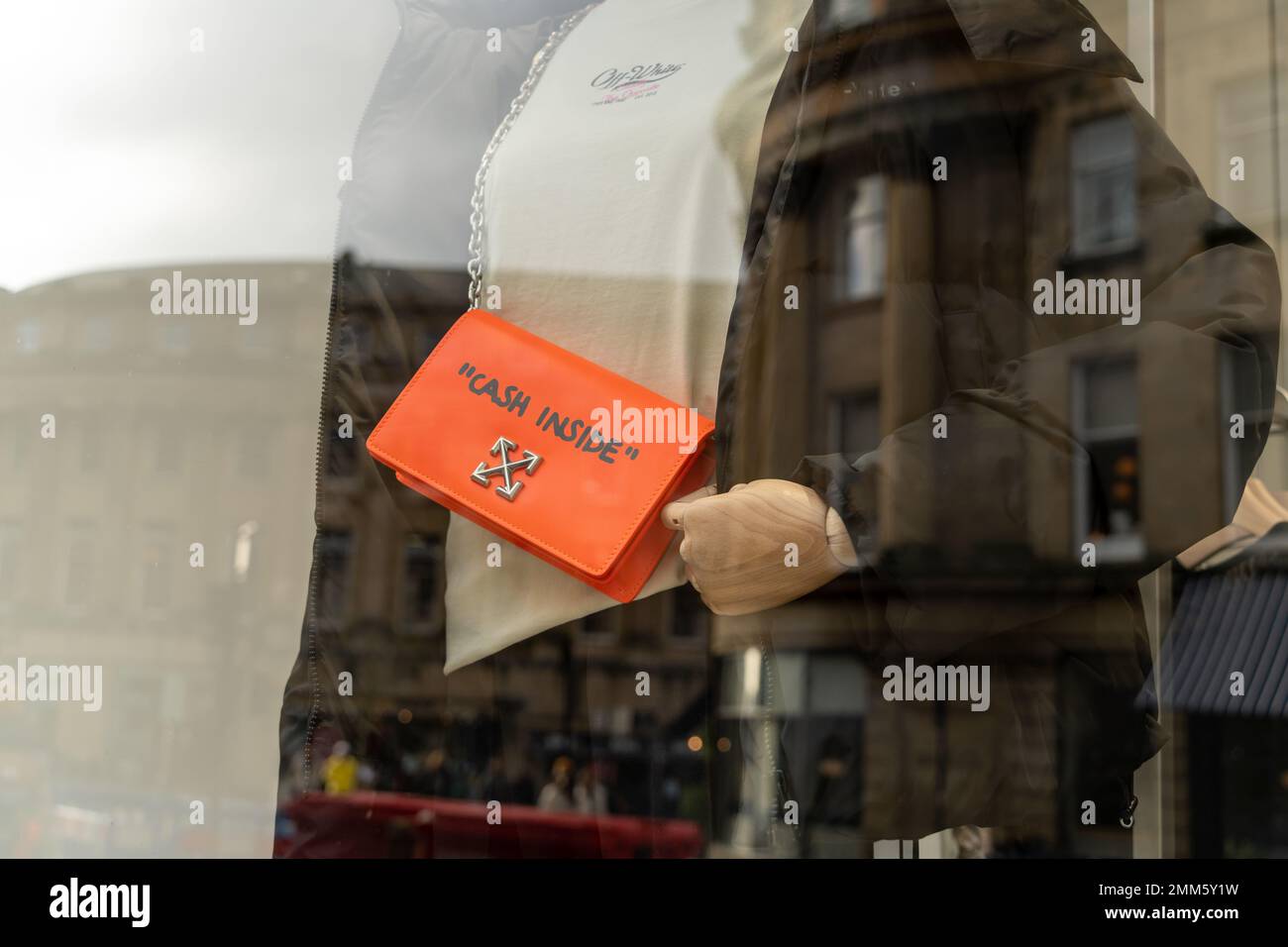 A shop window display dummy wears an orange shoulder bag by OFF-WHITE ...