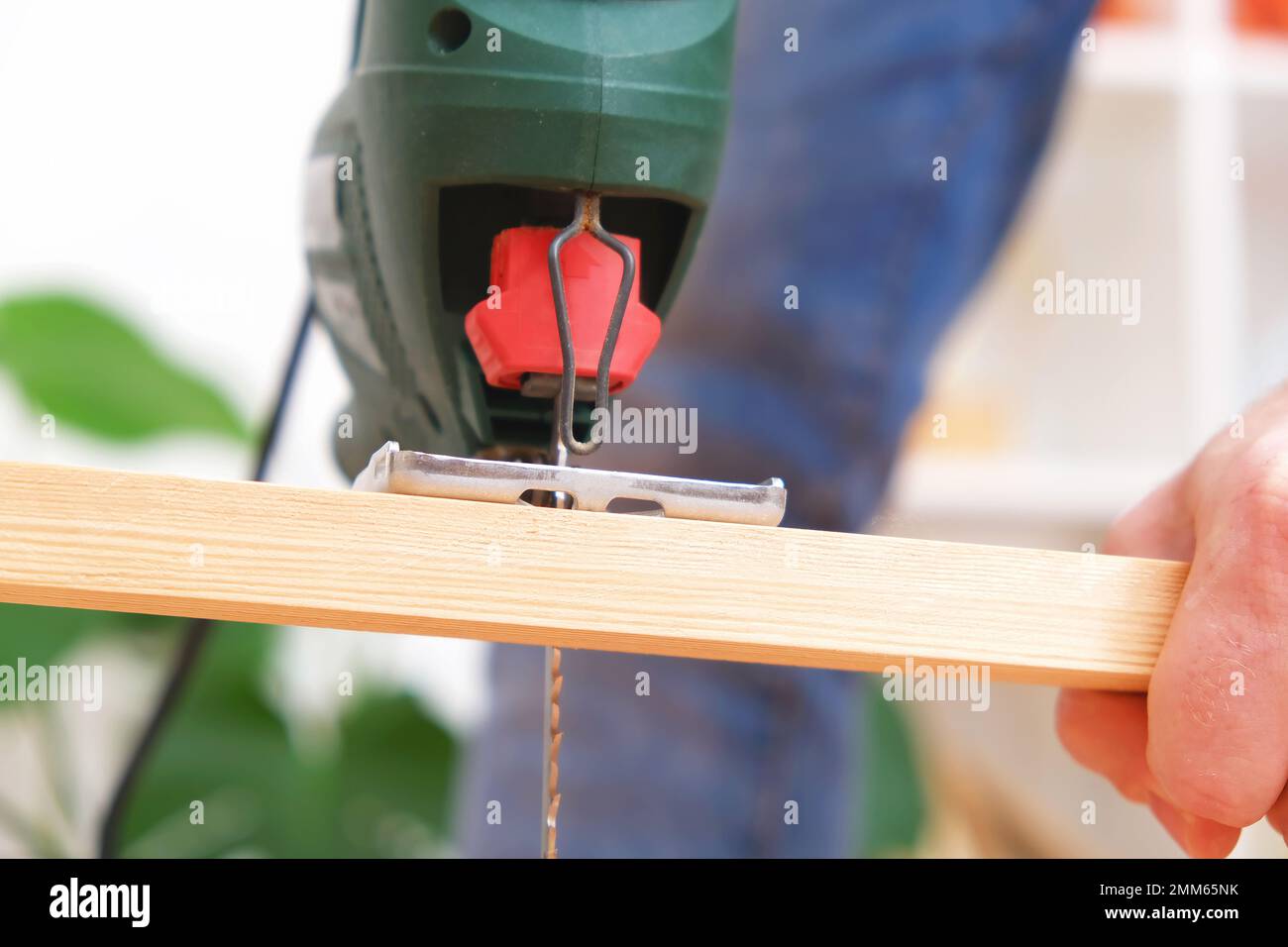 The hands of a master carpenter with an electric jigsaw in his hands ...