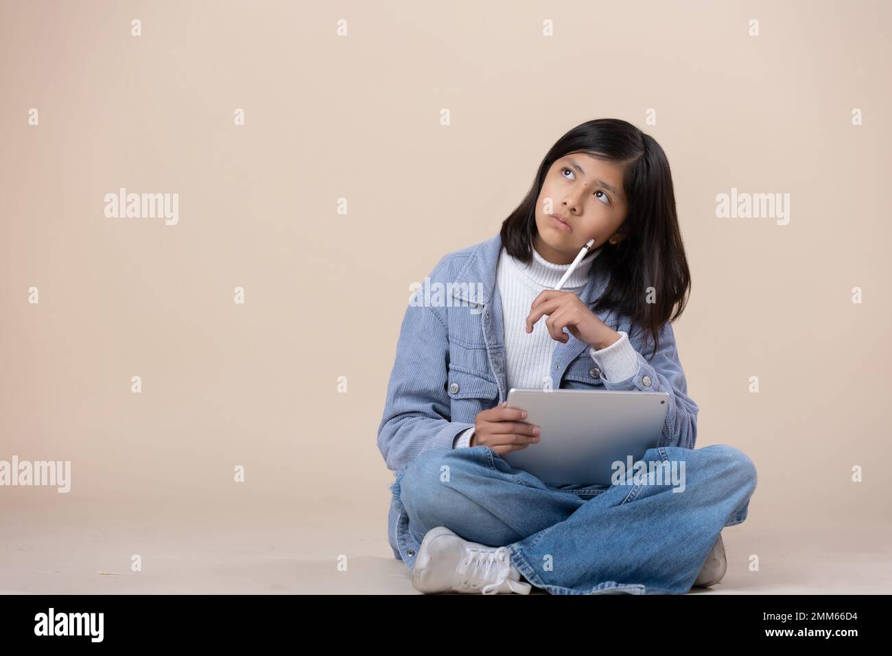 Mexican girl sitting on the floor thinking expression with table Stock ...