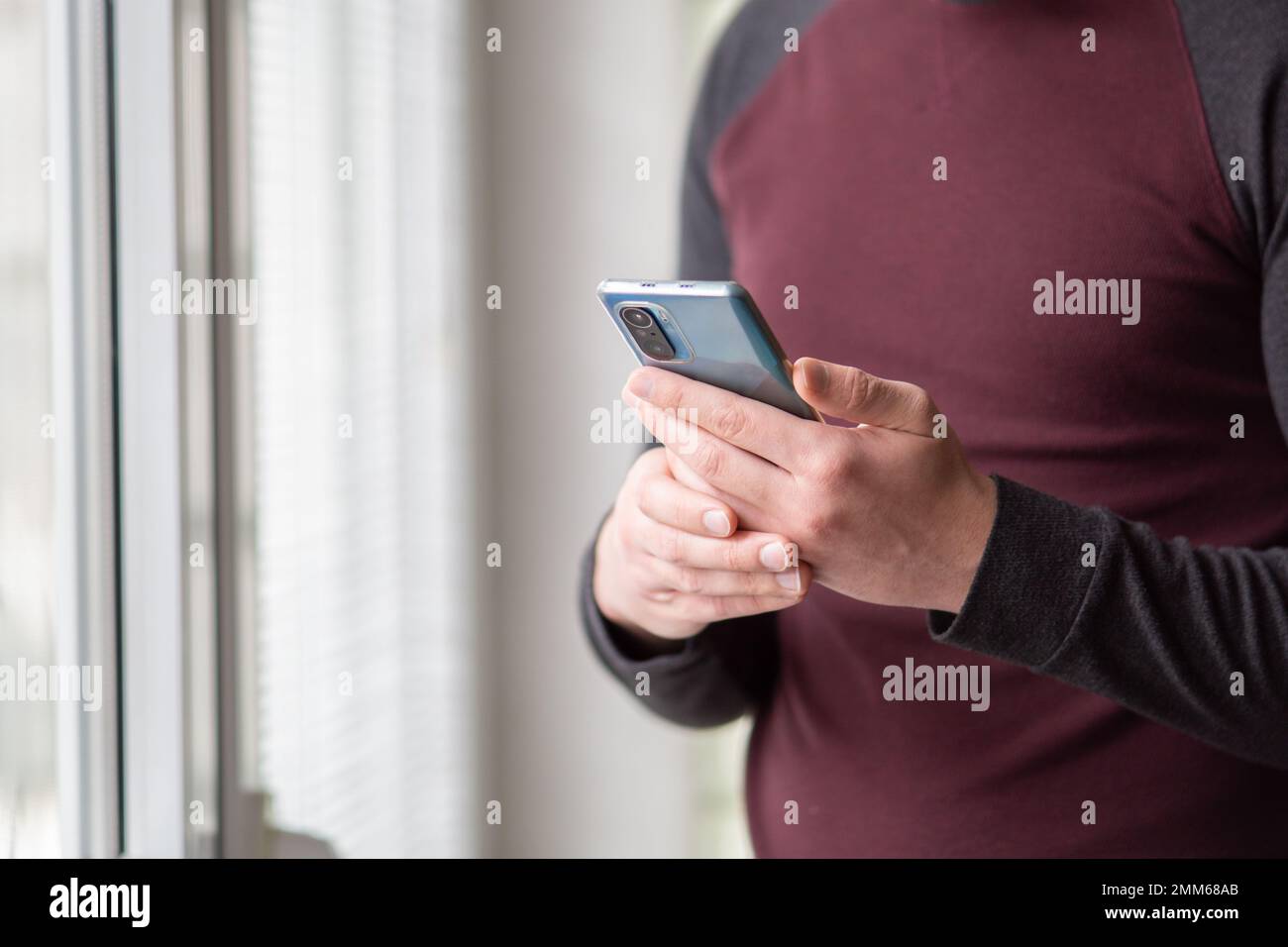 Close up of a man in sweater standing in front of windows at home and ...