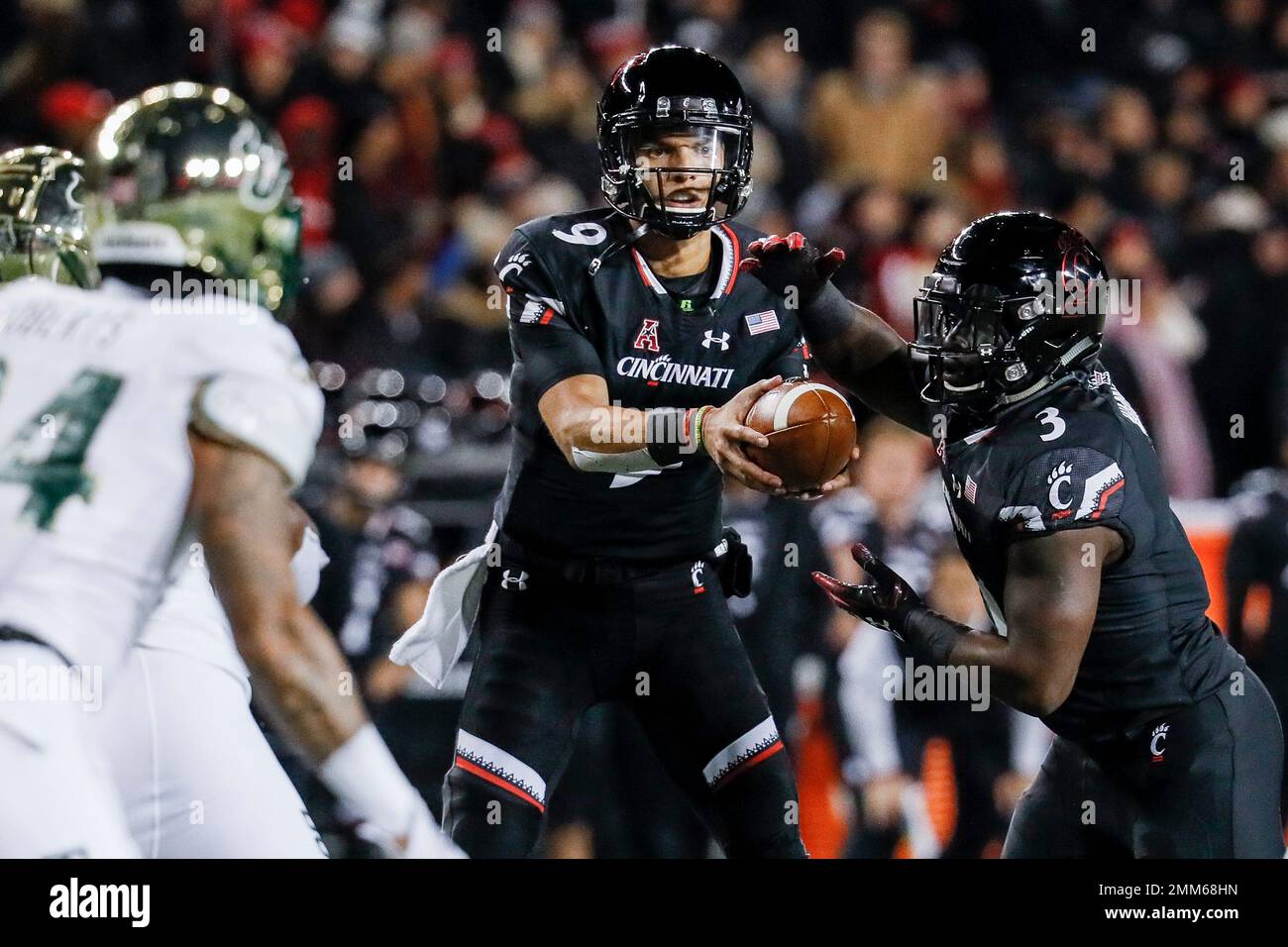 Cincinnati quarterback Desmond Ridder (9) hands the ball off to running ...