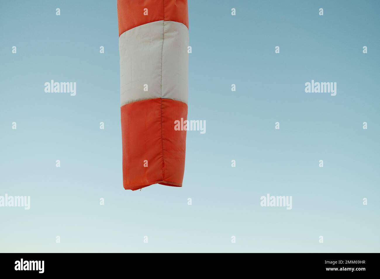 Red and white wind indicator against light blue sky Stock Photo - Alamy