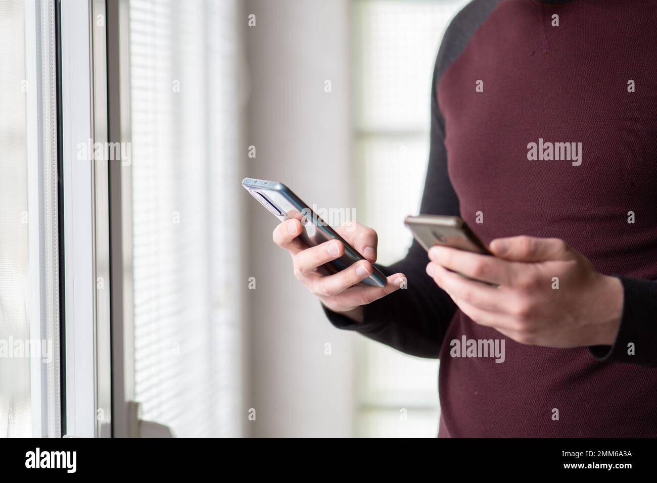 Close up of a man holding two smartphones. Man using two phones at the ...