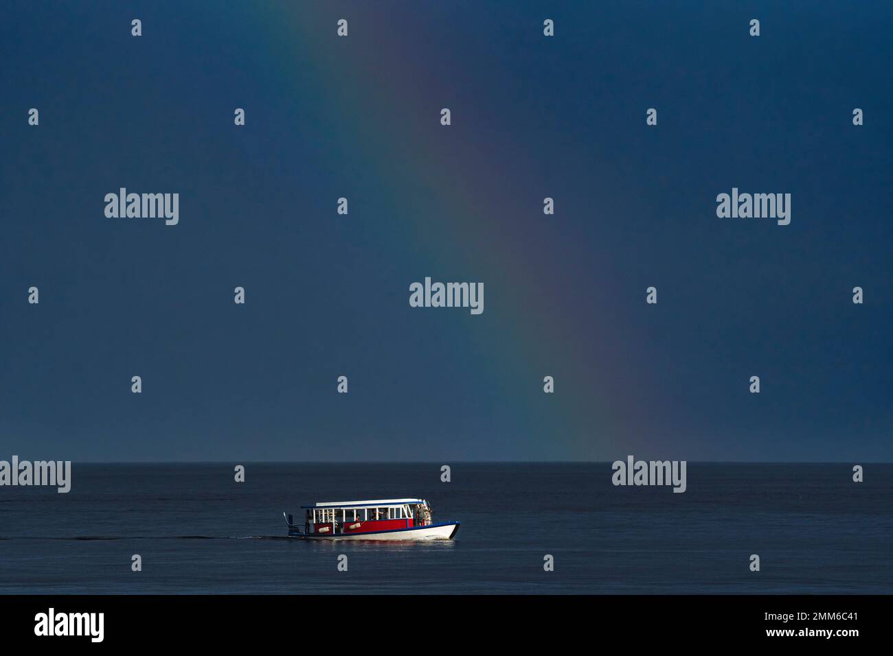 Red boat in the ocean under a rainbow Stock Photo - Alamy