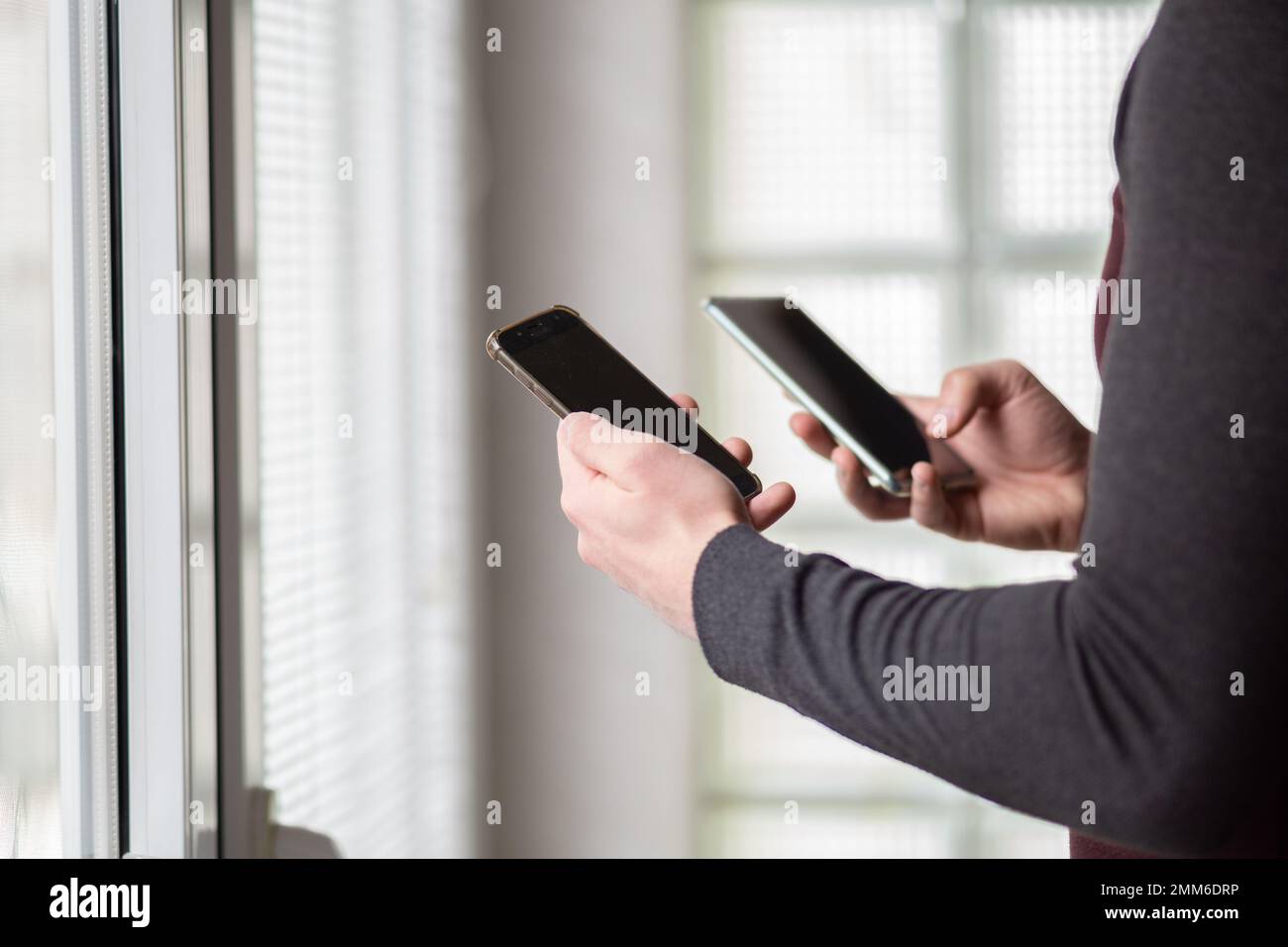 Close up of a man holding two smartphones. Man using two phones at the ...