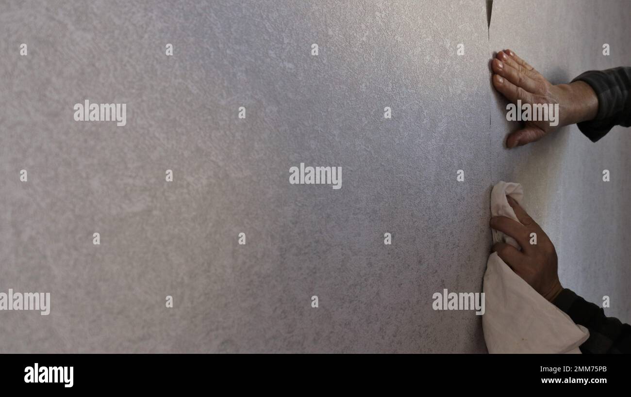 connecting two strips of gray textured wallpaper glued to the wall and ...