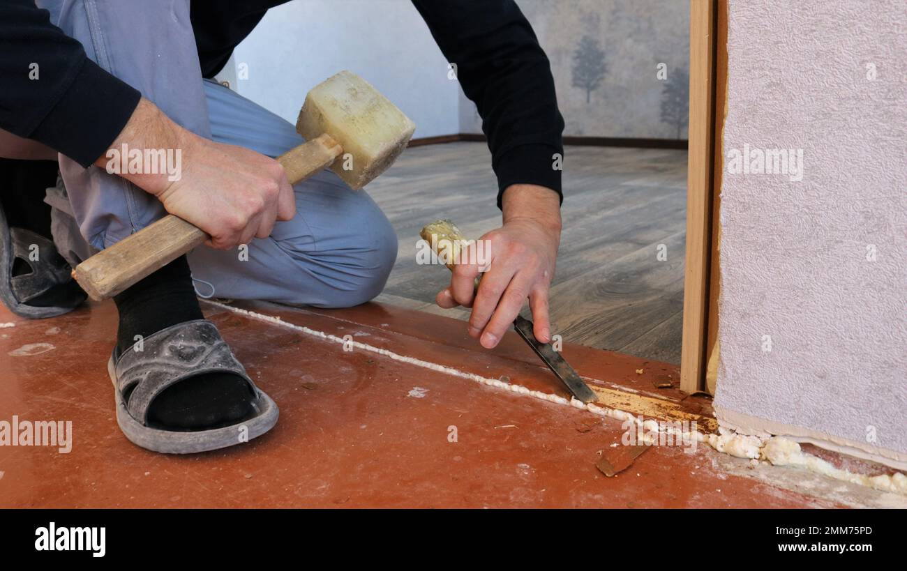 carpenter works with a mallet and a chisel in a home room leveling a ...