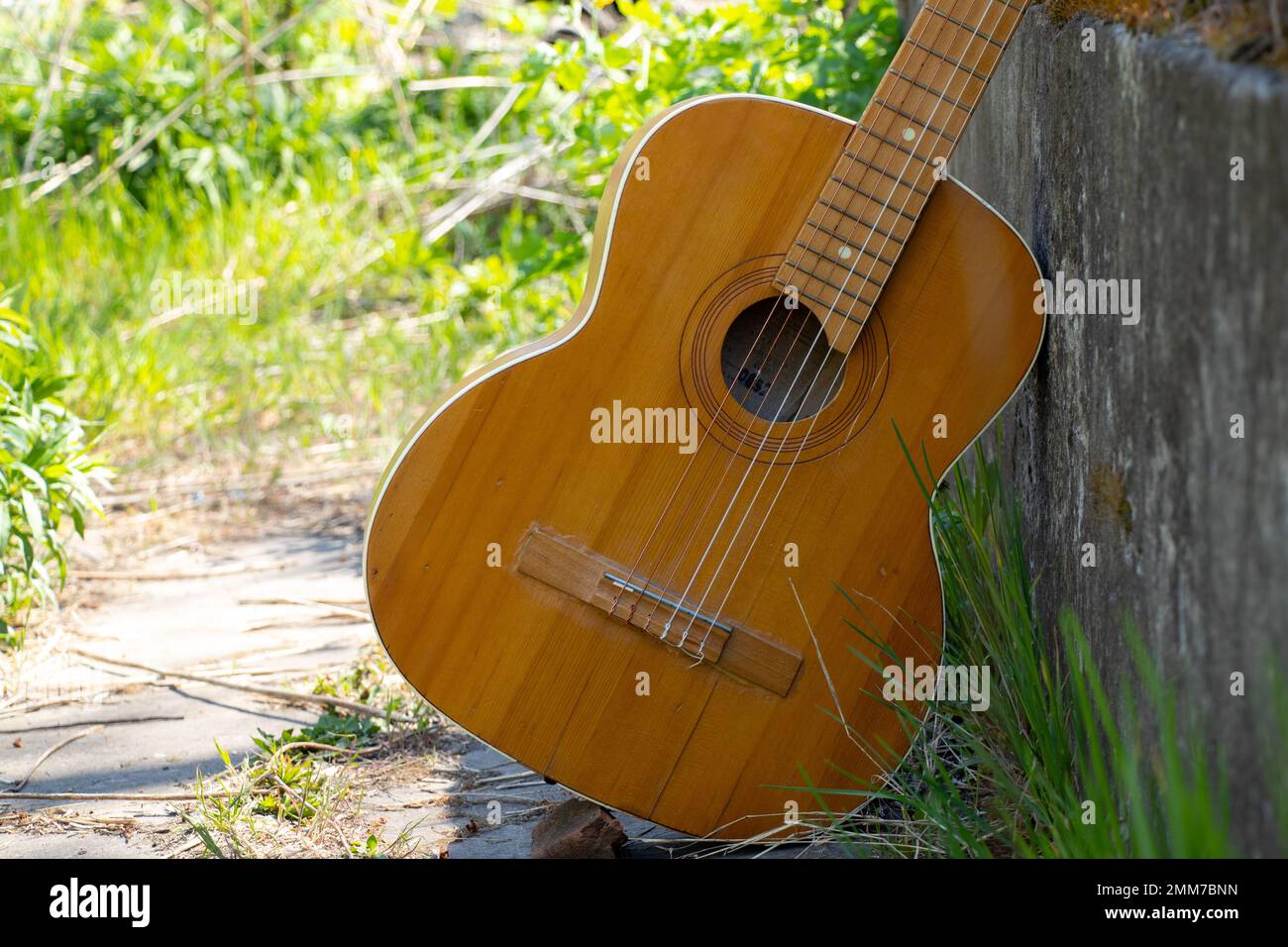 wooden brown guitar lies on a stone road in the street in the spring ...