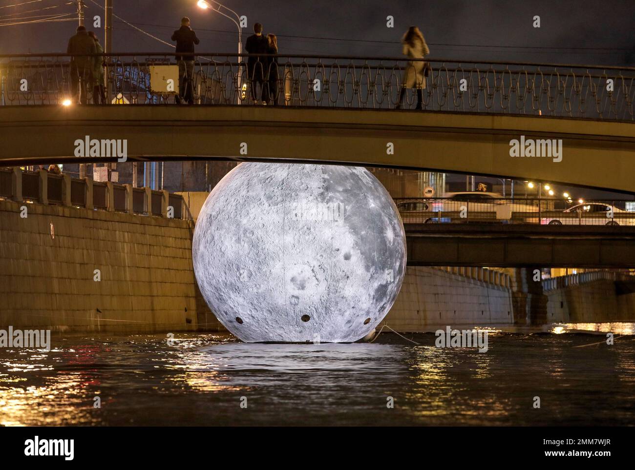 People look at a giant floating ball depicting the moon's surface, an ...