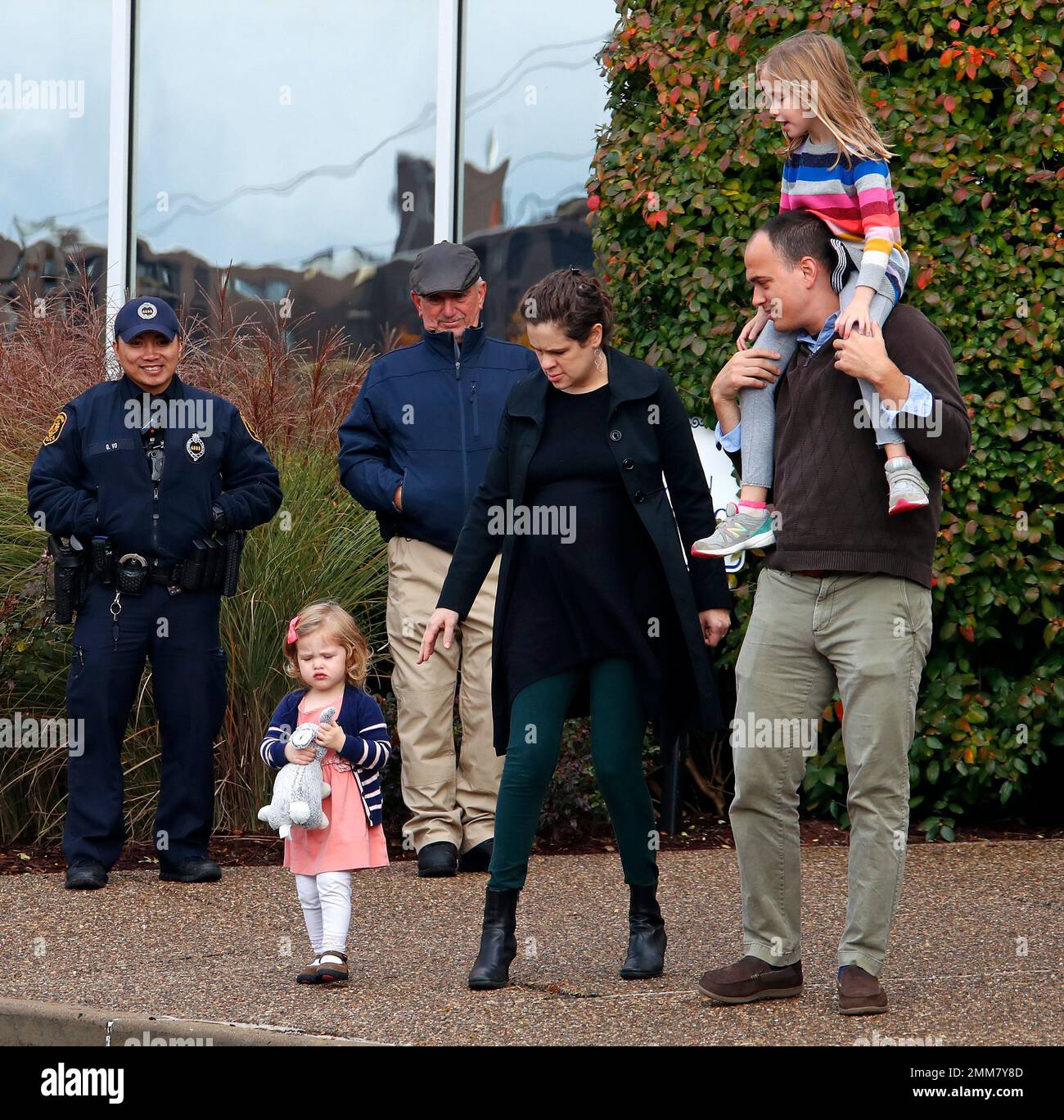 A family walks past a Pittsburgh Police officer, and a private security ...