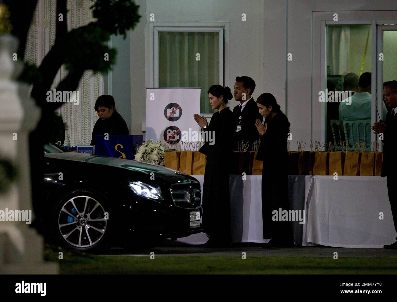 Ushers greet departing funeral guests outside a Buddhist funeral ...