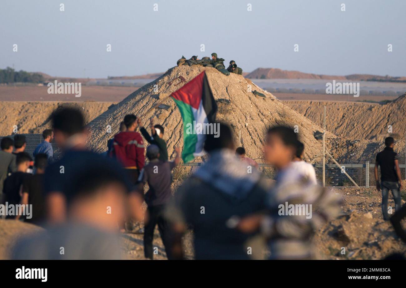 Israeli soldiers take positions on top of a sand berm in front of ...