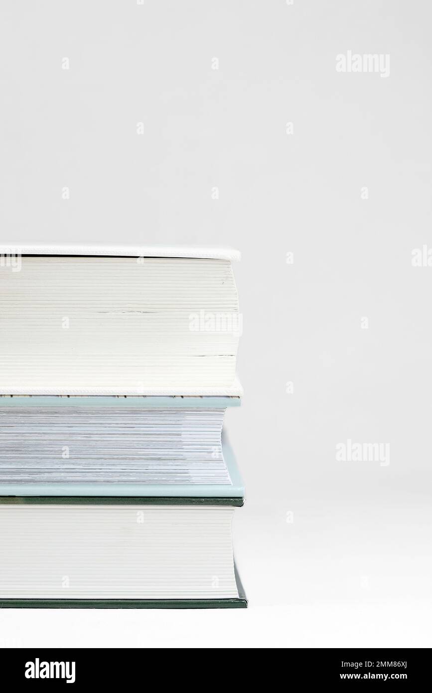 three thick books on a table with a white background Stock Photo - Alamy