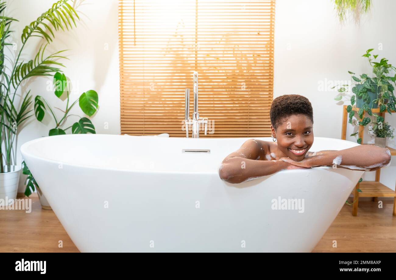 Luxury bath portrait of an attractive African woman relaxing in bathtub ...
