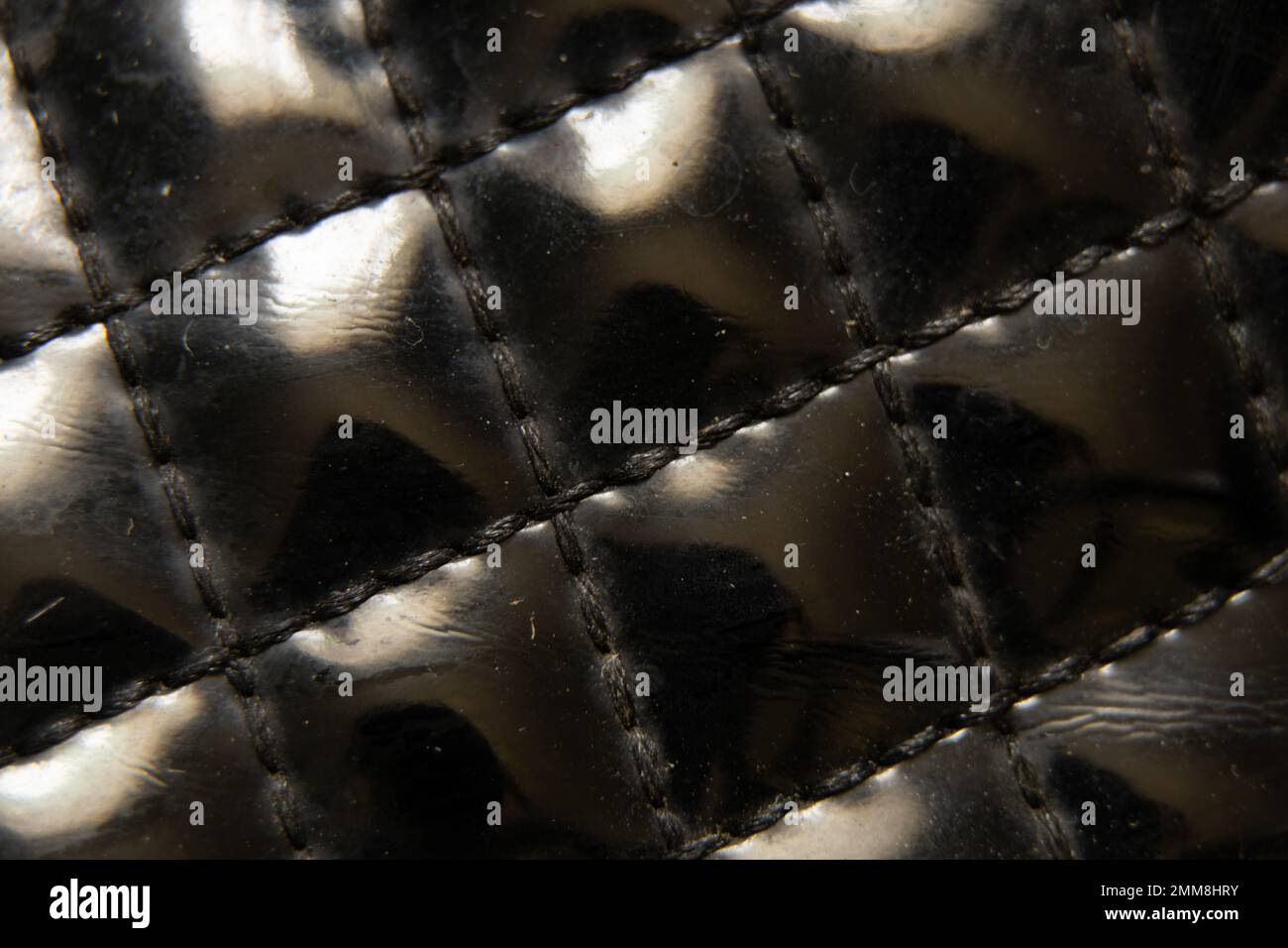 black patent leather stitched with threads as a background, macro photo ...
