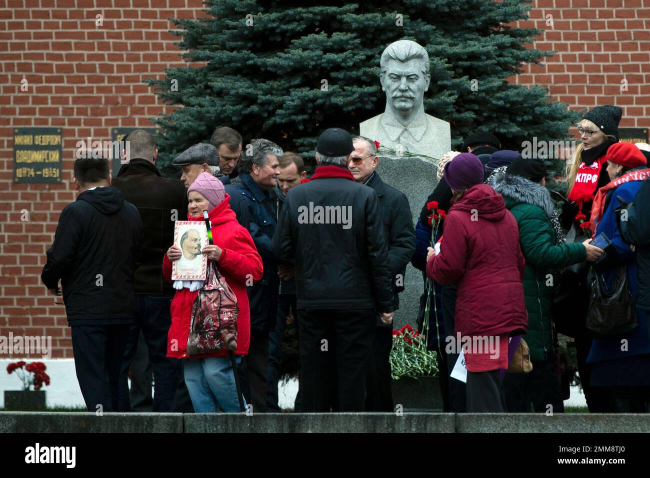 An elderly woman holds a portrait of the Soviet founder Vladimir Lenin ...