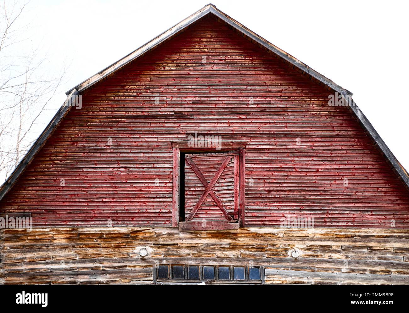 Close Up Of Exterior Top Half Of Large Old Red Weathered Barn With A Door To The Loft And Row Of