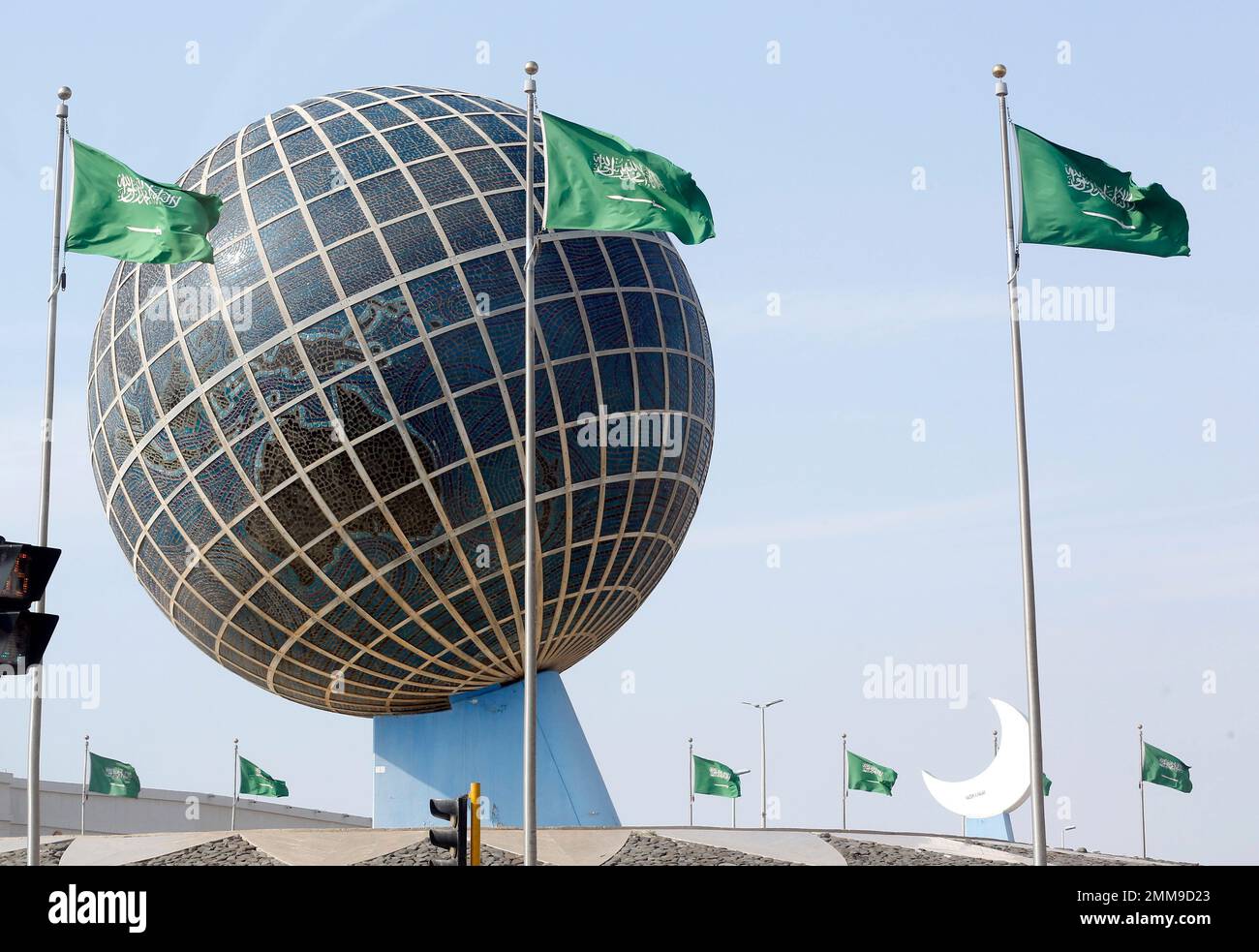 Saudi Arabia flags surround an object representing the globe at a ...