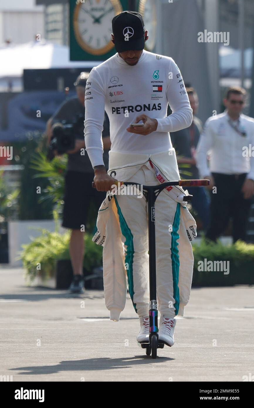 Mercedes driver Lewis Hamilton, of Britain, rides a scooter to the pit ...