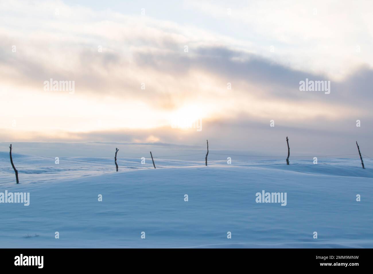 Sun Rising Behind a beautiful Winter Scene of Snow Covered Hills and an ...