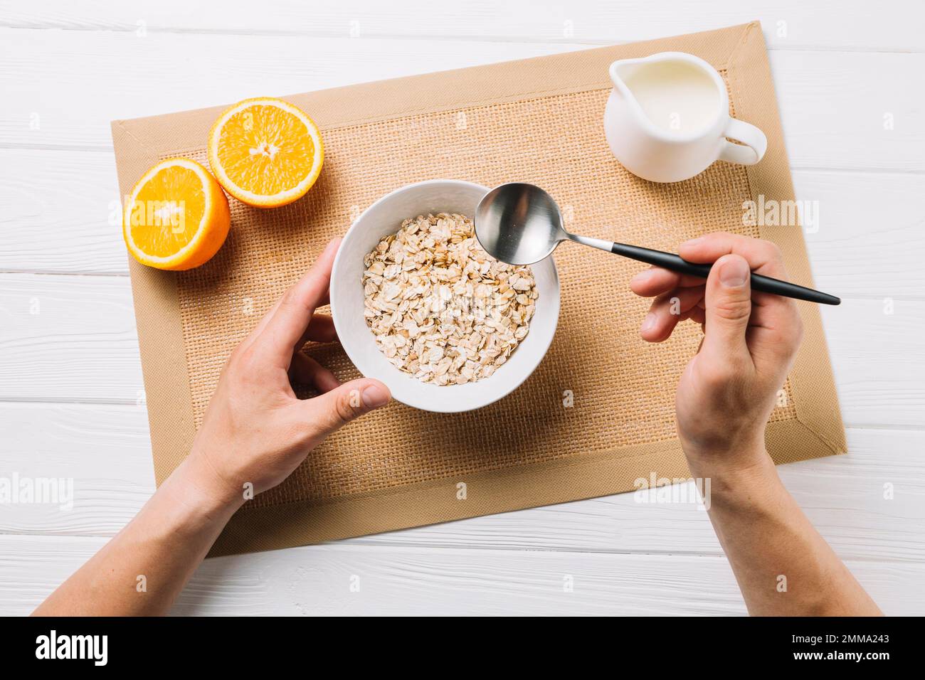 person having oatmeal halved orange milk jute placemat white surface ...