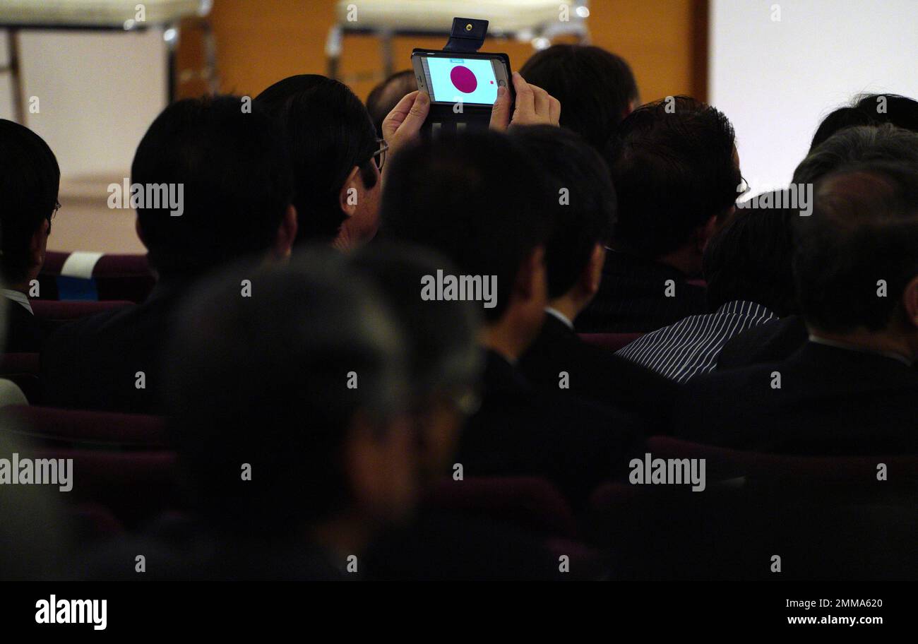 A guest takes a photo of a Japanese national flag at a ceremony marking ...