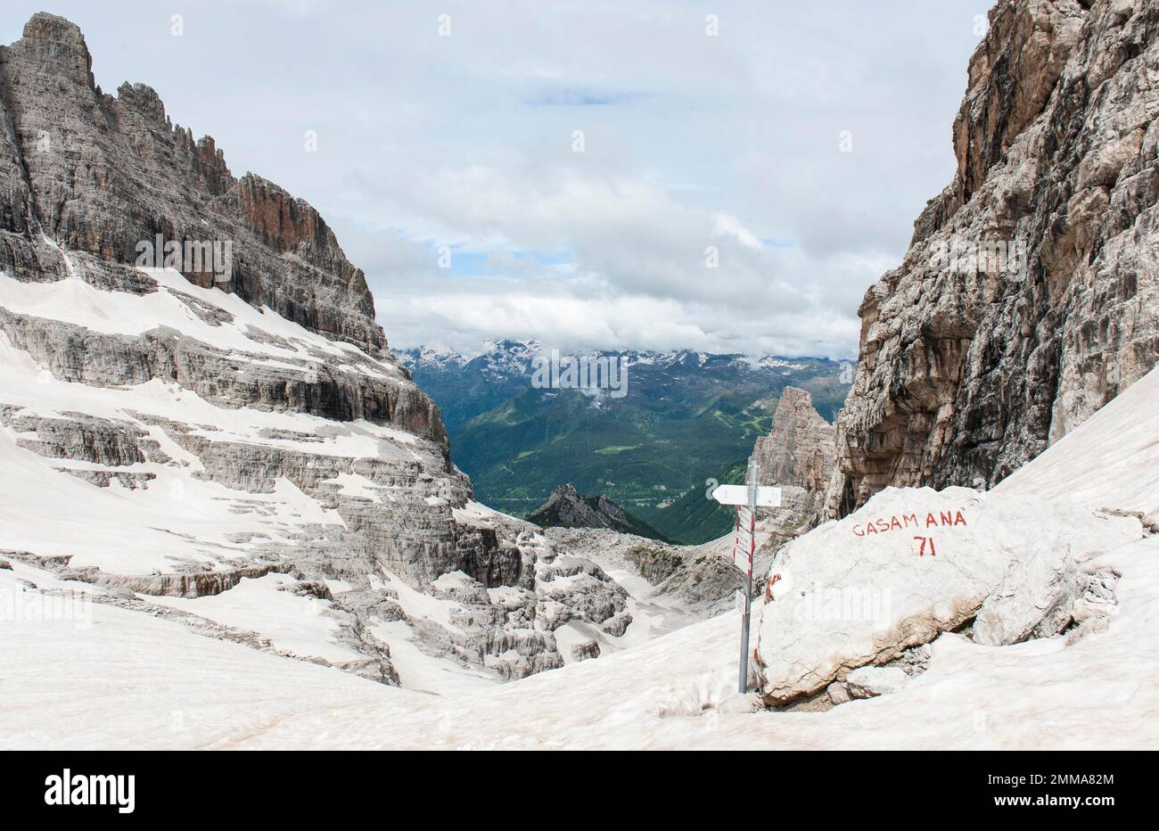 Snow-covered pass Bocca del Tuckett with hiking sign, entrance to via ...