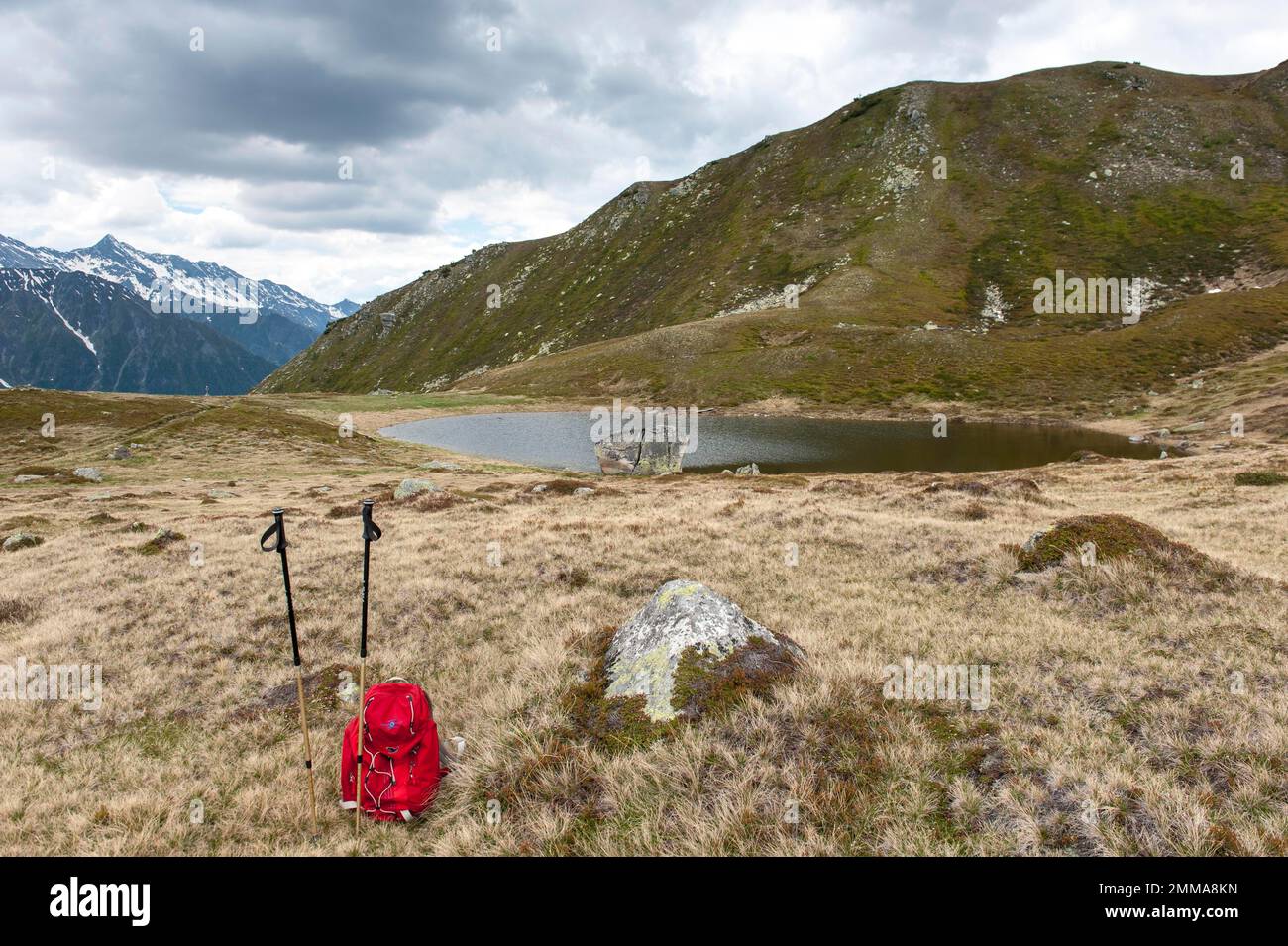Hiking backpack and hiking poles, small mountain lake, near St. Peter, Ahrntal, Valle Aurina ...