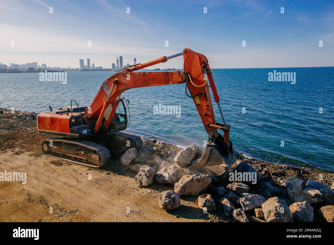 Excavator working on earthmoving at construction of new embankment ...